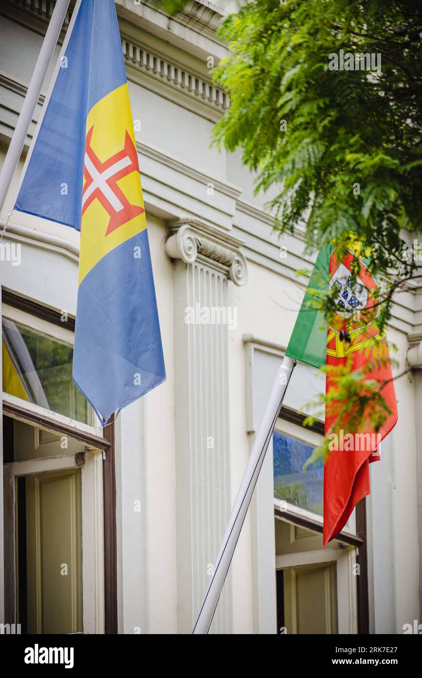 A low angle shot of flags displayed on a building in Funchal, Madeira ...