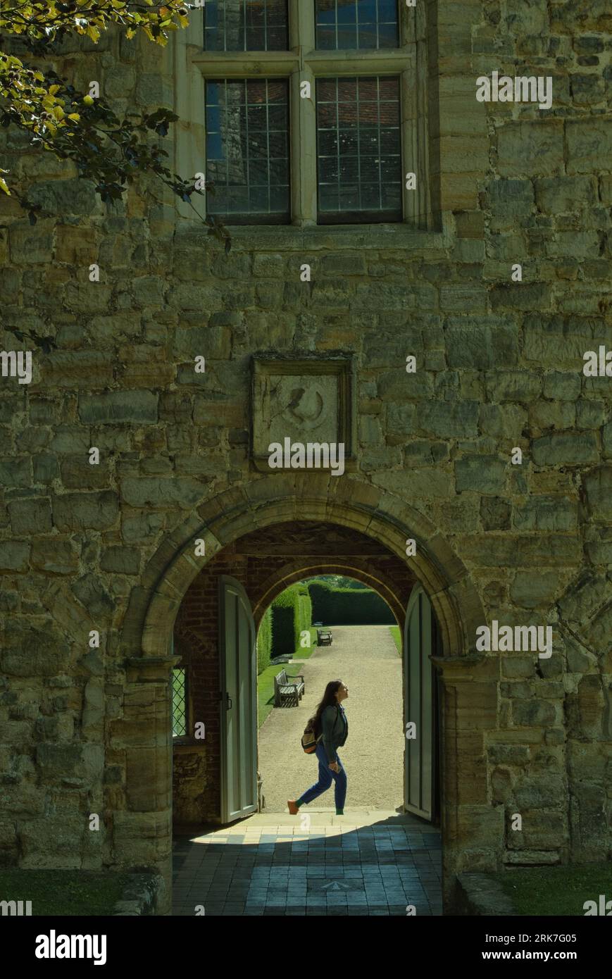 woman visitor walking past the gate house in Penshurst Place Manor House in Penshurst, Kent in ...