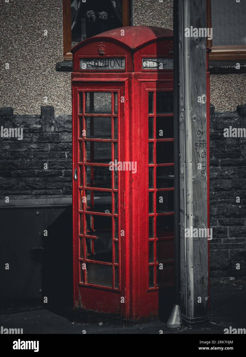 A vintage red telephone booth positioned in front of a historic brick ...