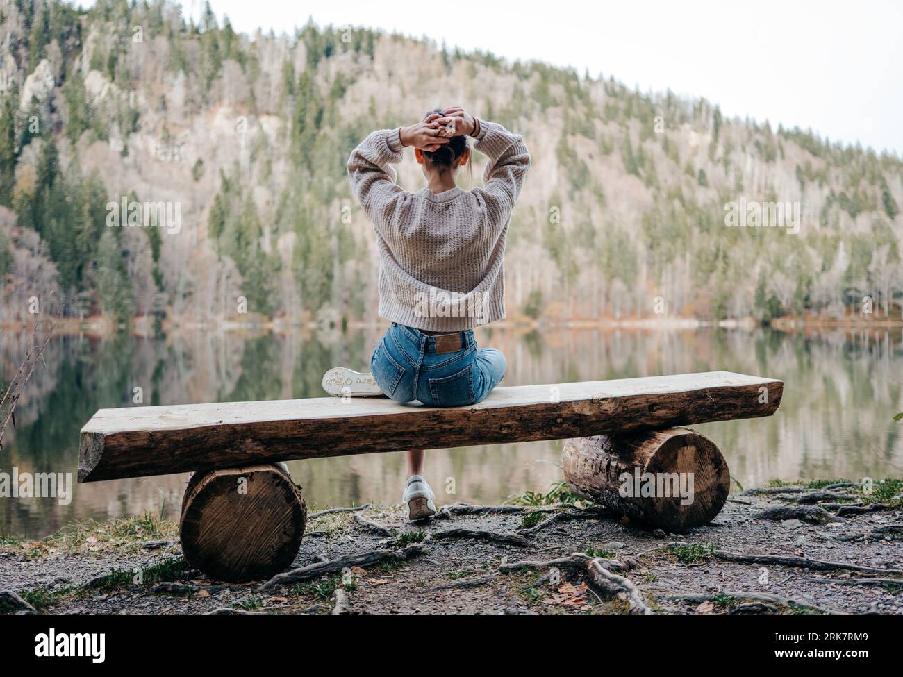 A young woman sitting on a log in an outdoor setting Stock Photo - Alamy