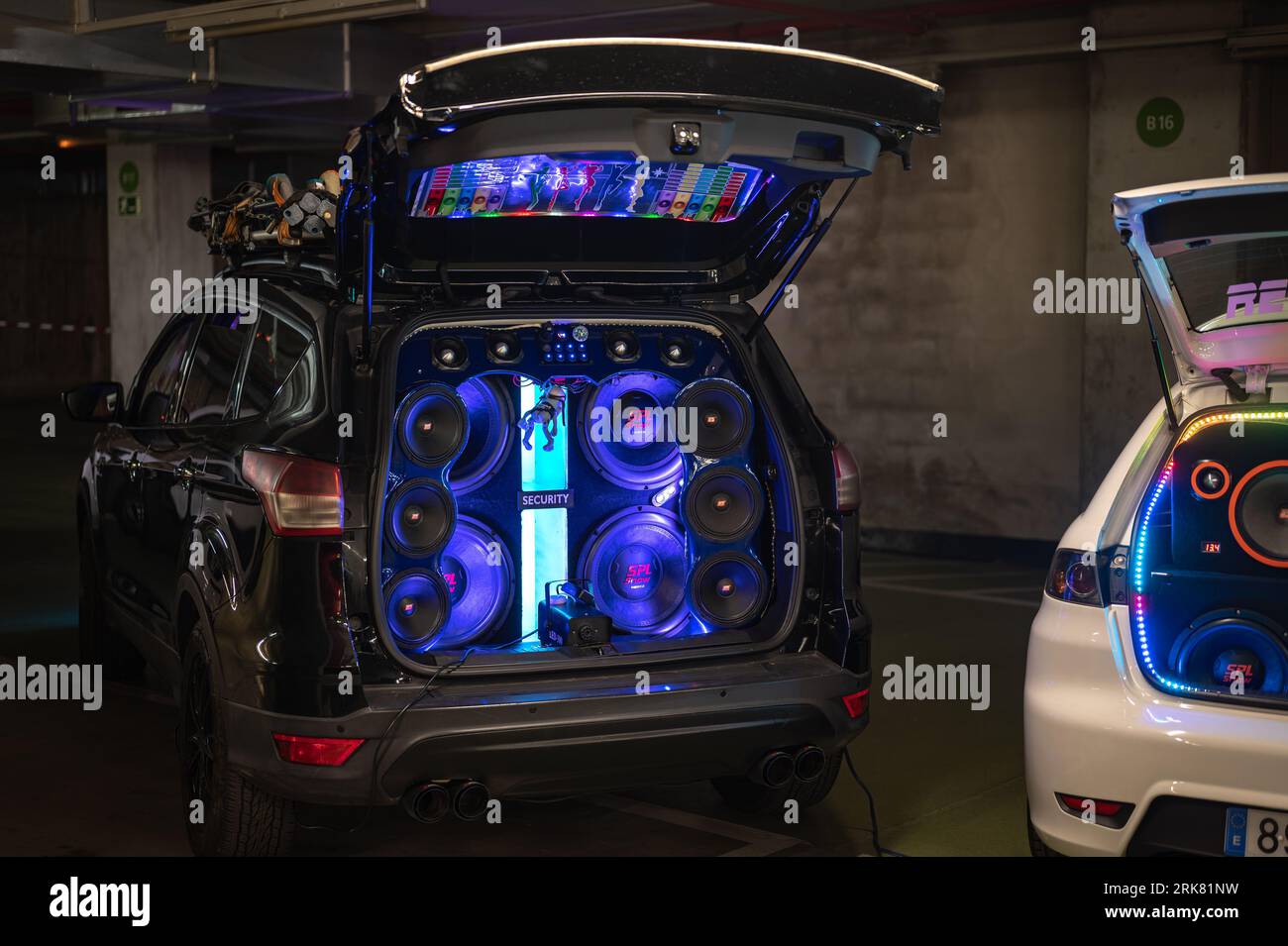 A black Ford Kuga SUV with an open trunk full of neon speakers and ...
