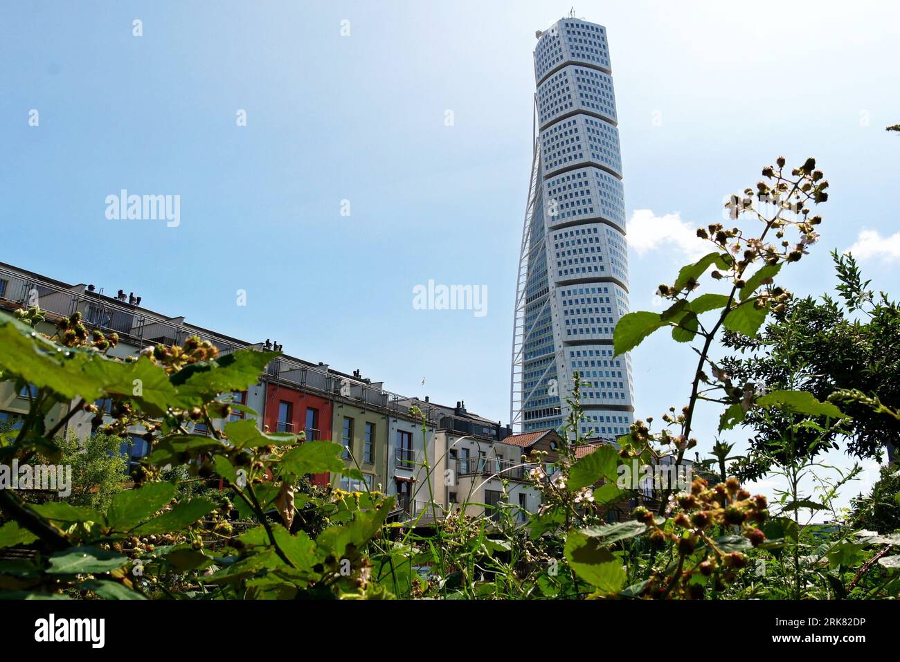 A vertical high-rise building in the background, with lush greenery in ...