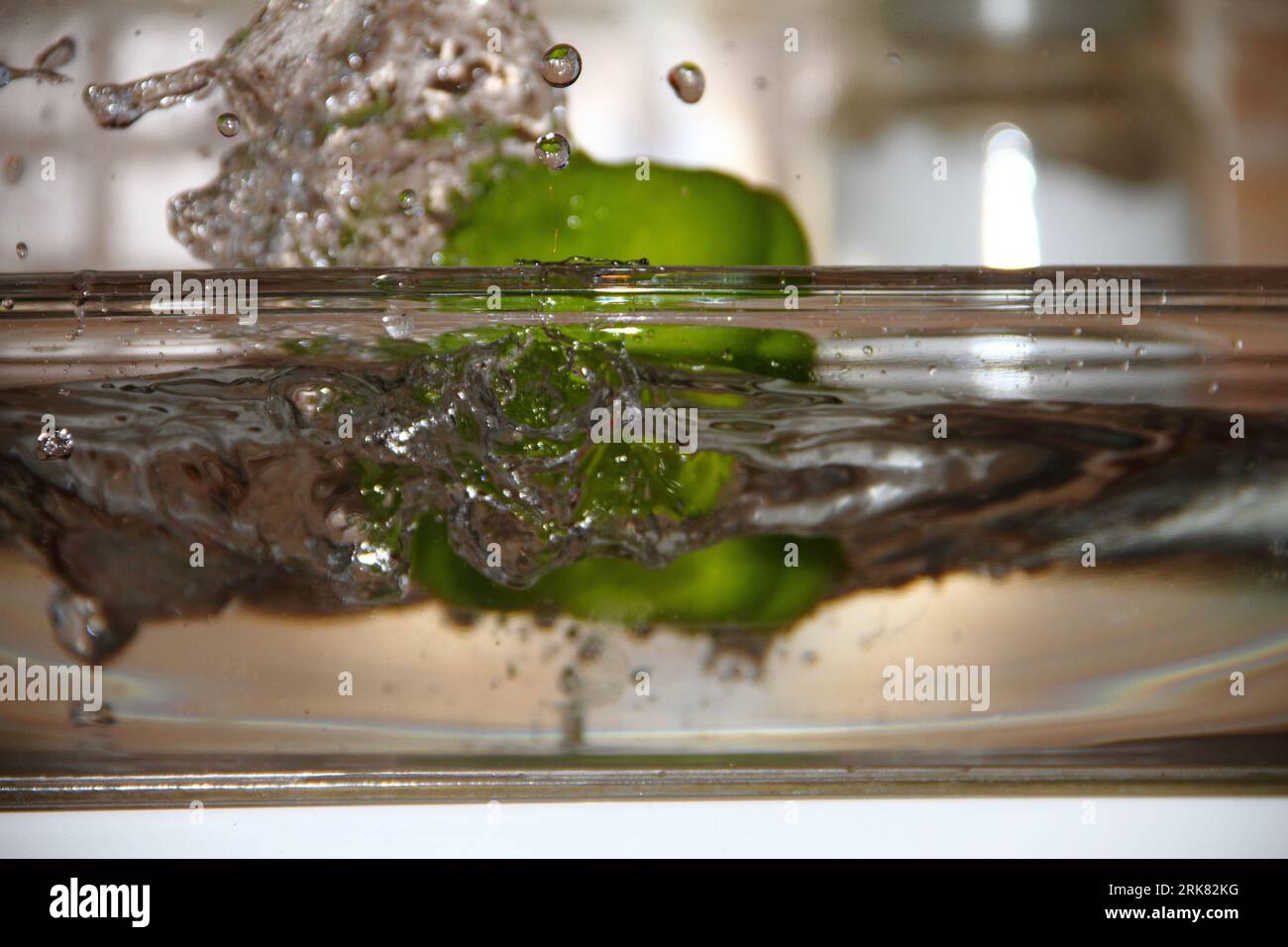 A green vegetable sitting in a body of water, sitting on a light wood ...