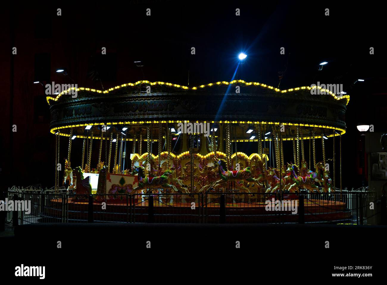 Colorful carousel illuminated at night with bright overhead lights ...