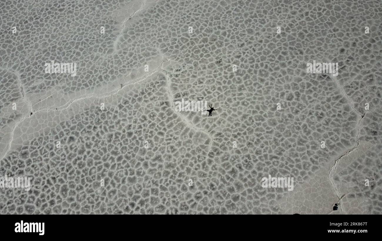 An aerial view of a people reclining on a dry, cracked sandy landscape ...