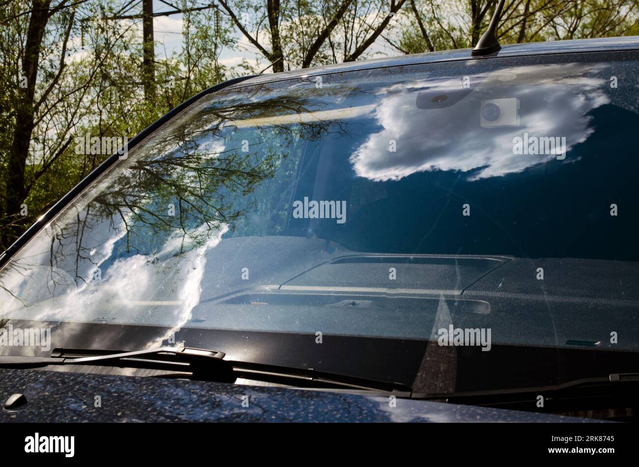Clouds reflection on the car window, modern car standing under the ...