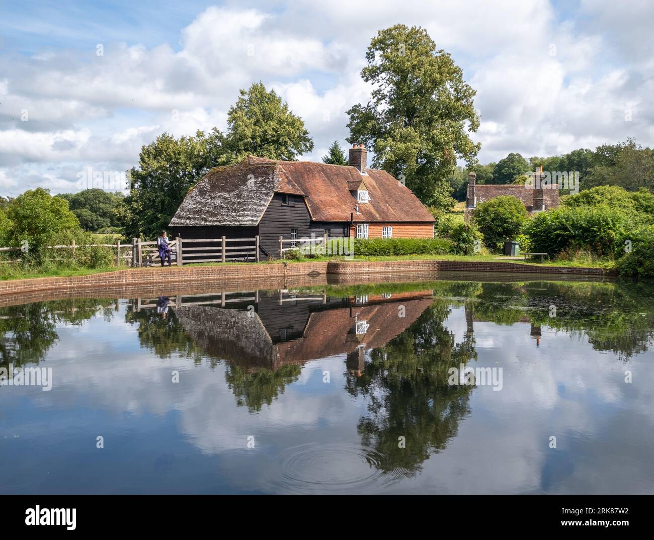 A traditional house is situated near a tranquil pond, and its ...