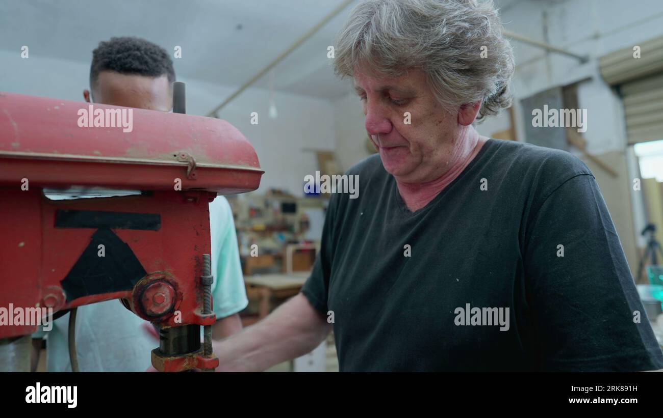 Senior Carpenter using industrial machine to make a hole into wooden ...