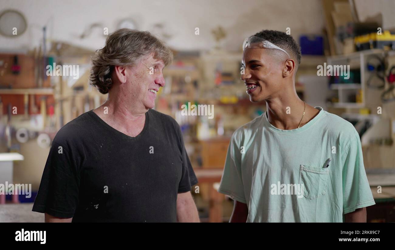 Portrait of senior and apprentice carpenters standing inside wood ...