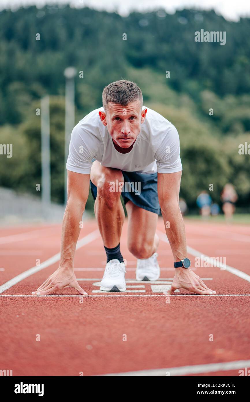 A fit, active man stands on a marked start line, ready to begin a ...