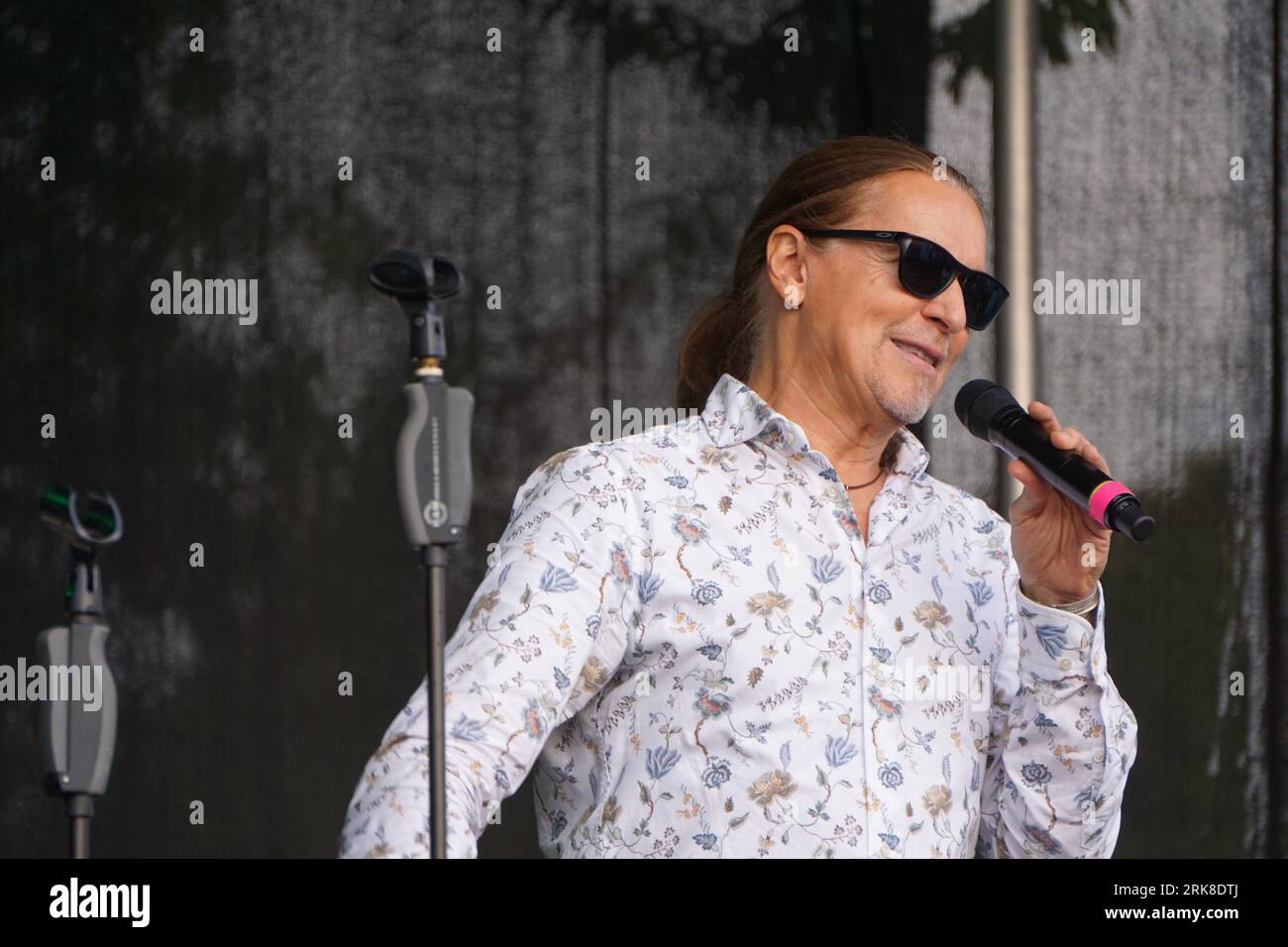 A solo adult male stands confidently in front of a microphone on a ... A solo adult male stands confidently in front of a microphone on a ...