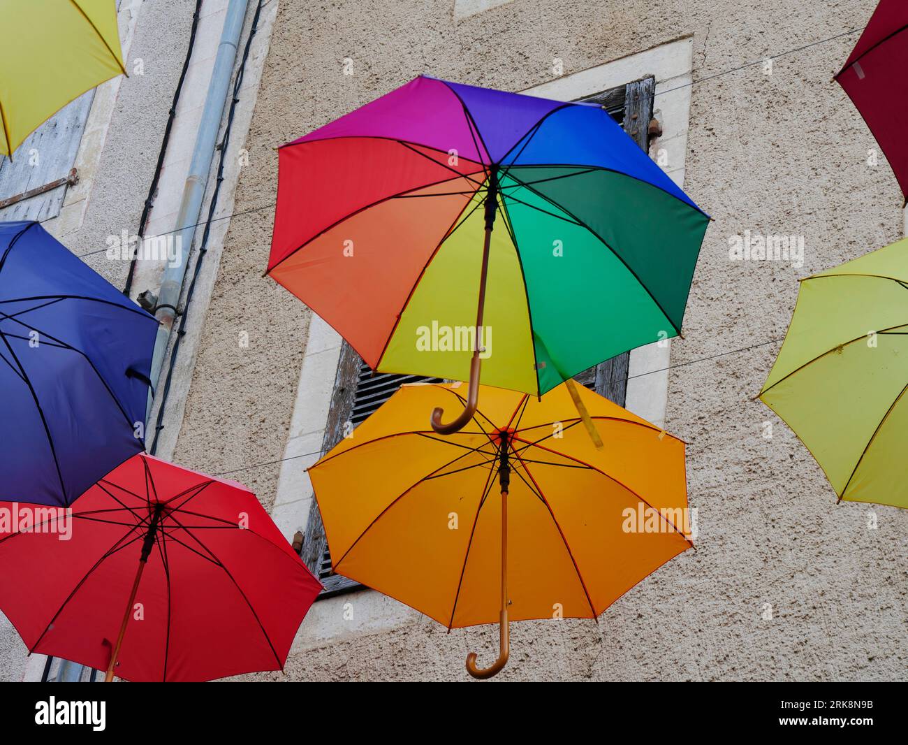 colorful floating umbrellas in the street in Puy l'Eveque. Rainbow ...