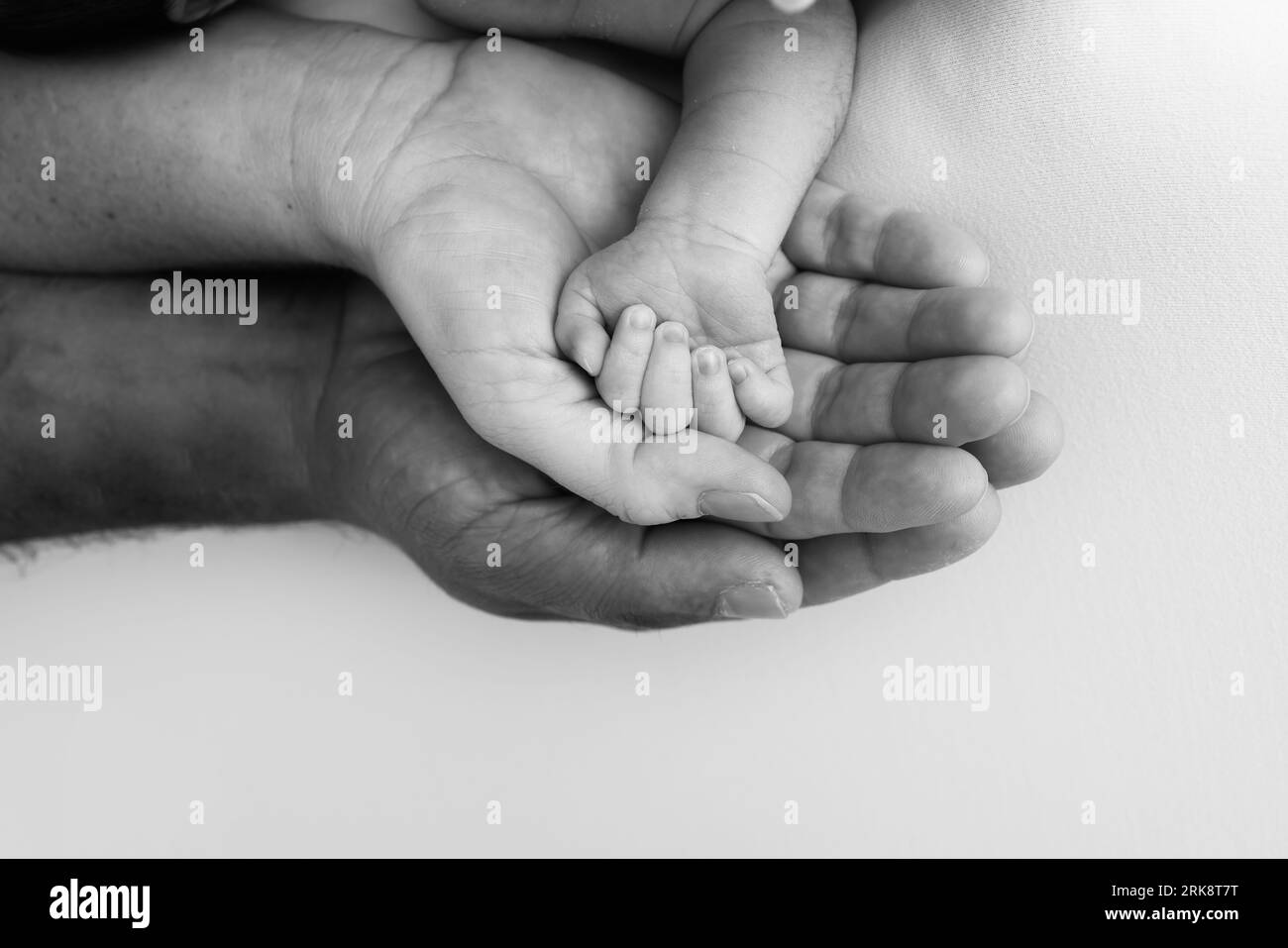 Small newborn hand with tiny fingers. The palm of parents, father and ...