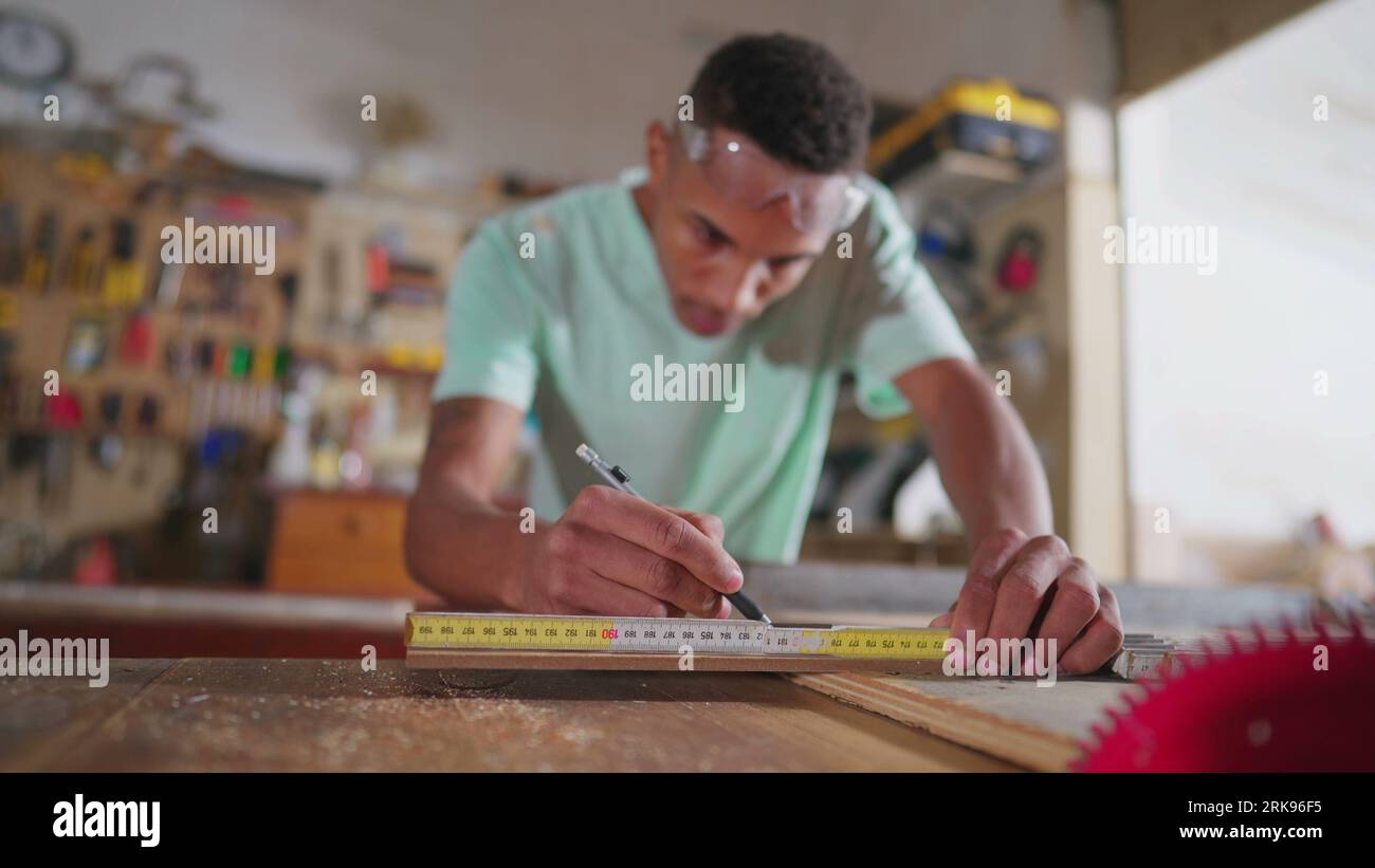One Young black carpentry student measuring wood, preparing to use saw ...