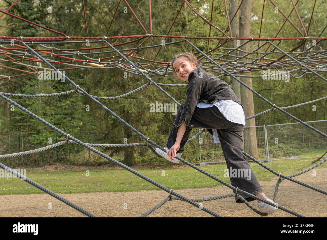 Teenage girl. looking at the camera, climbing on spider web with ...