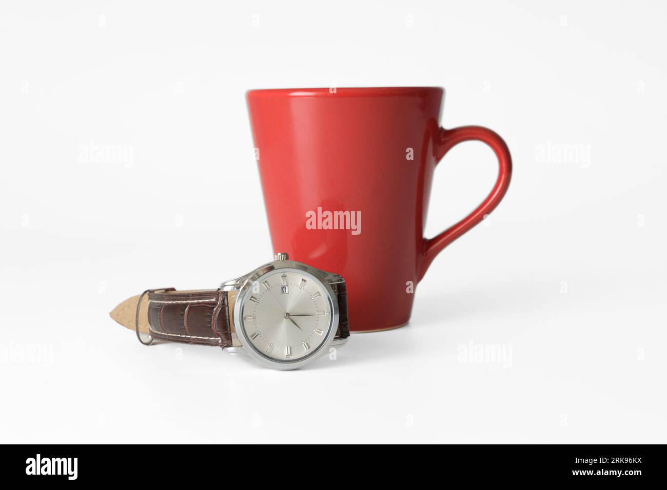 Time for coffee. Red mug and wrist watch on a strap on a white ...