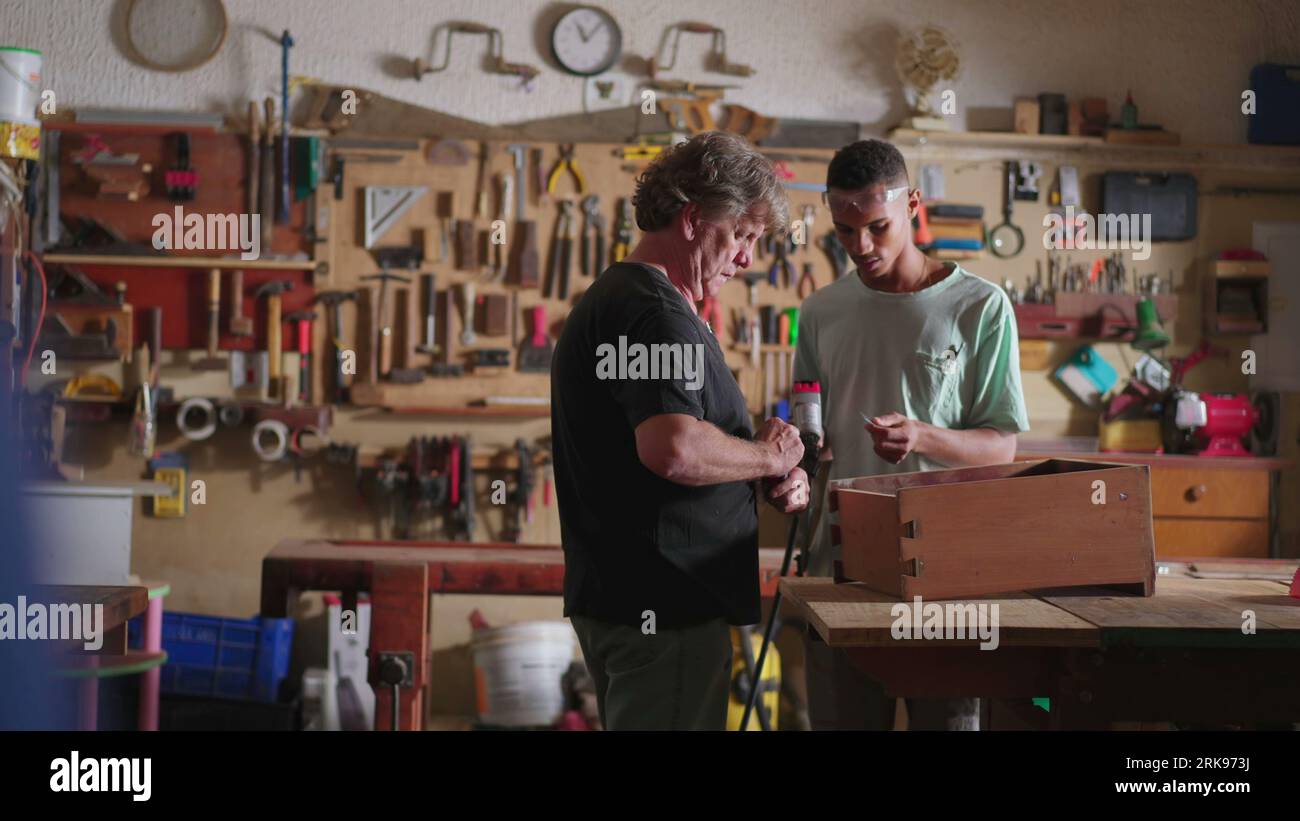 Candid scene of senior carpenter and junior apprentice young man ...