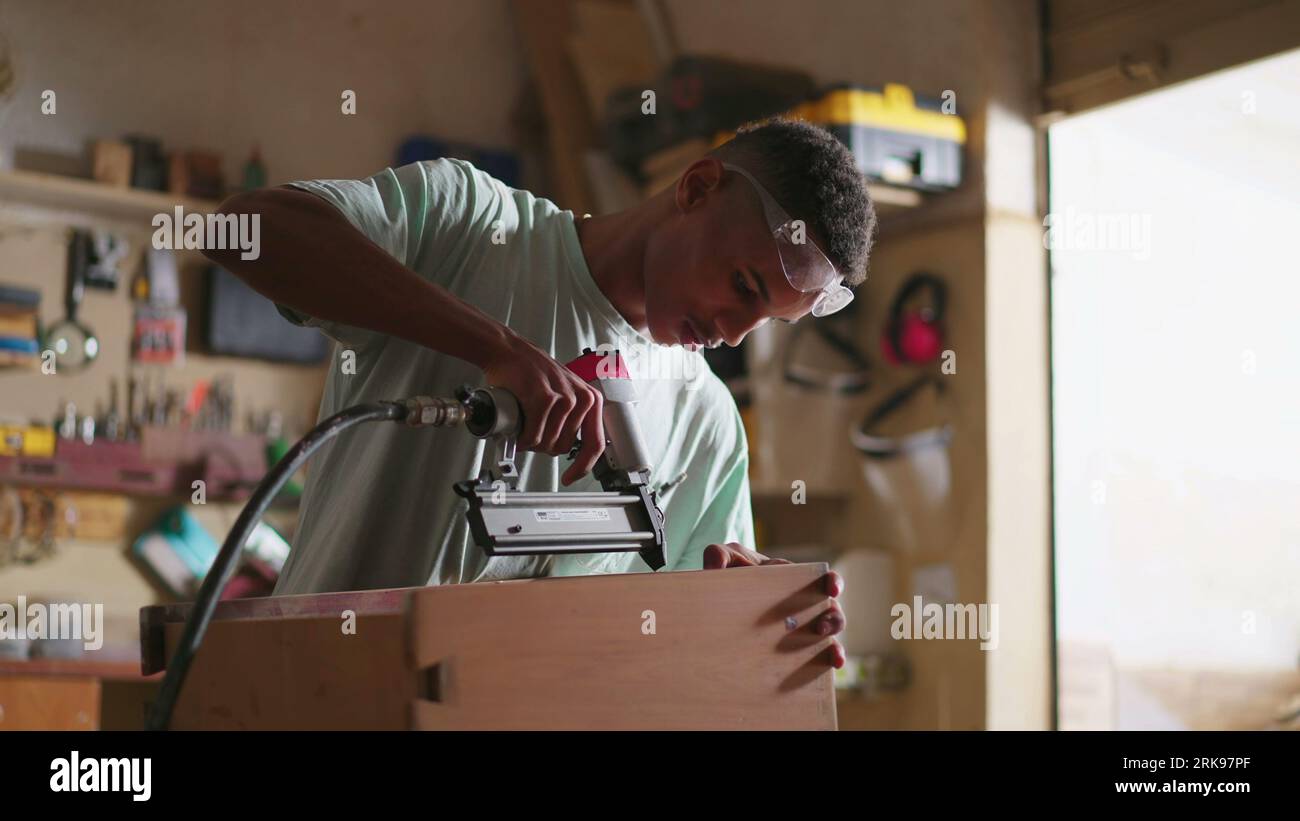 One young black carpenter building and fixing furniture at carpentry ...