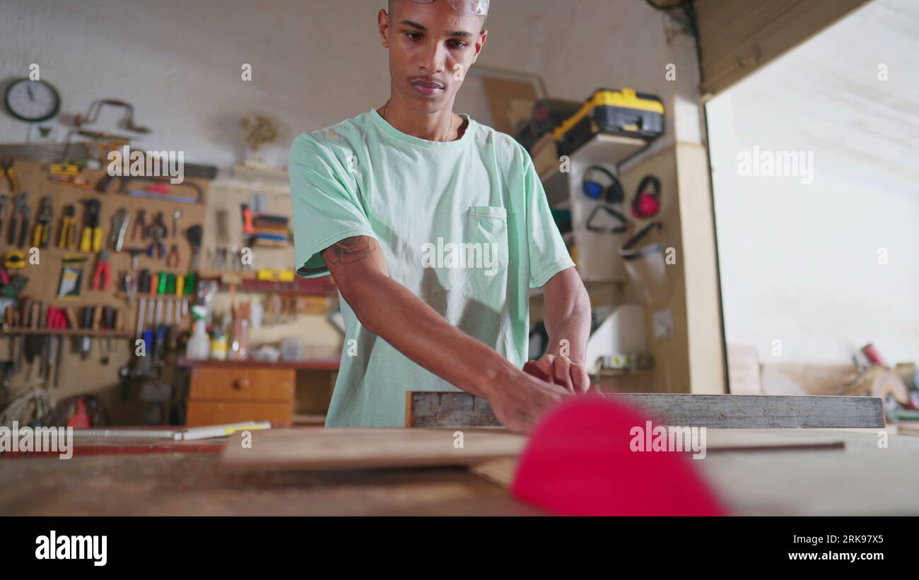 One Young black carpentry student measuring wood, preparing to use saw ...