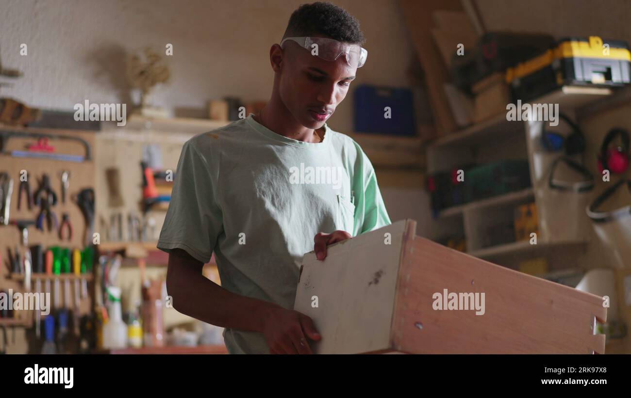 One young black carpenter building and fixing furniture at carpentry ...