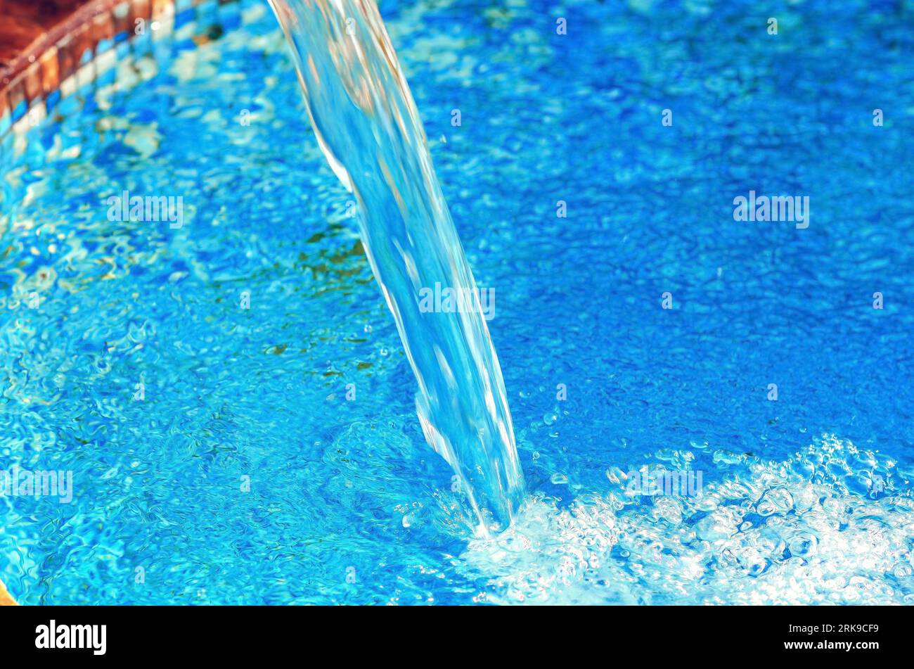 A stream of water flows into the pool. Blue water Stock Photo - Alamy