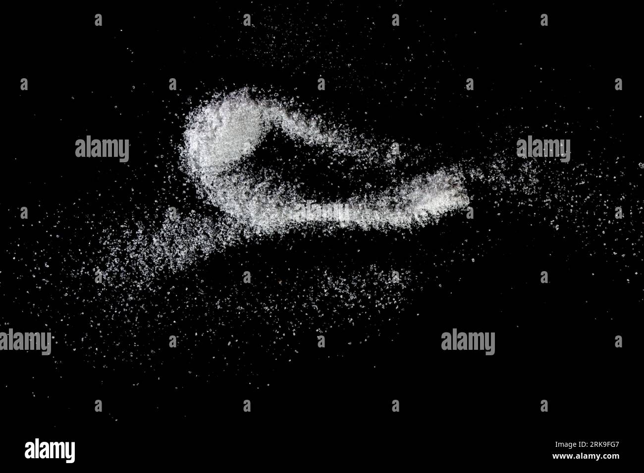 Spilled white sea salt on a black background. clear crystalline pebbles ...