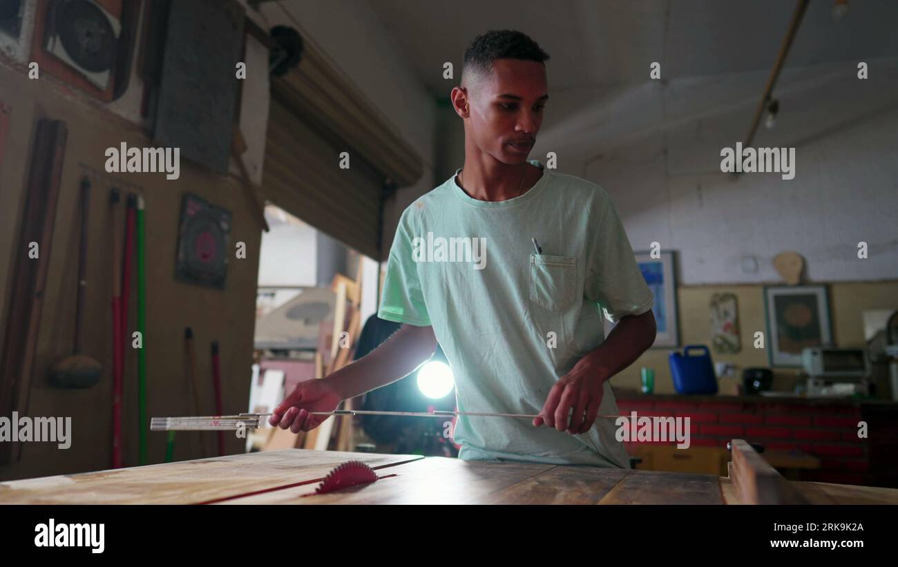 Woodworking apprentice measuring piece of wood in preparation for ...