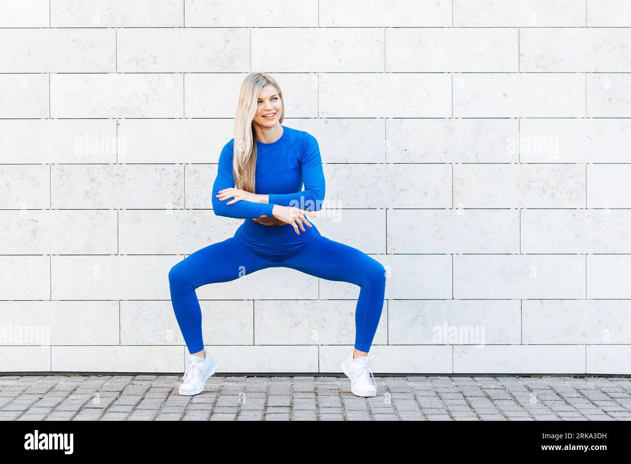 Fitness sport woman doing stretching exercise over gray wall ...