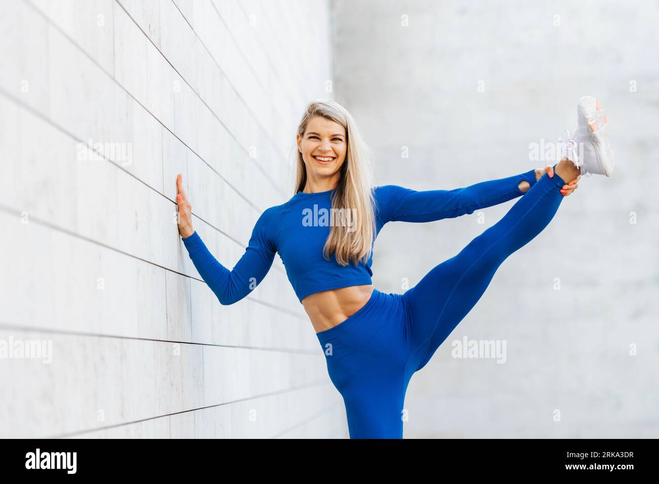 Fitness sport woman doing stretching exercise over gray wall ...