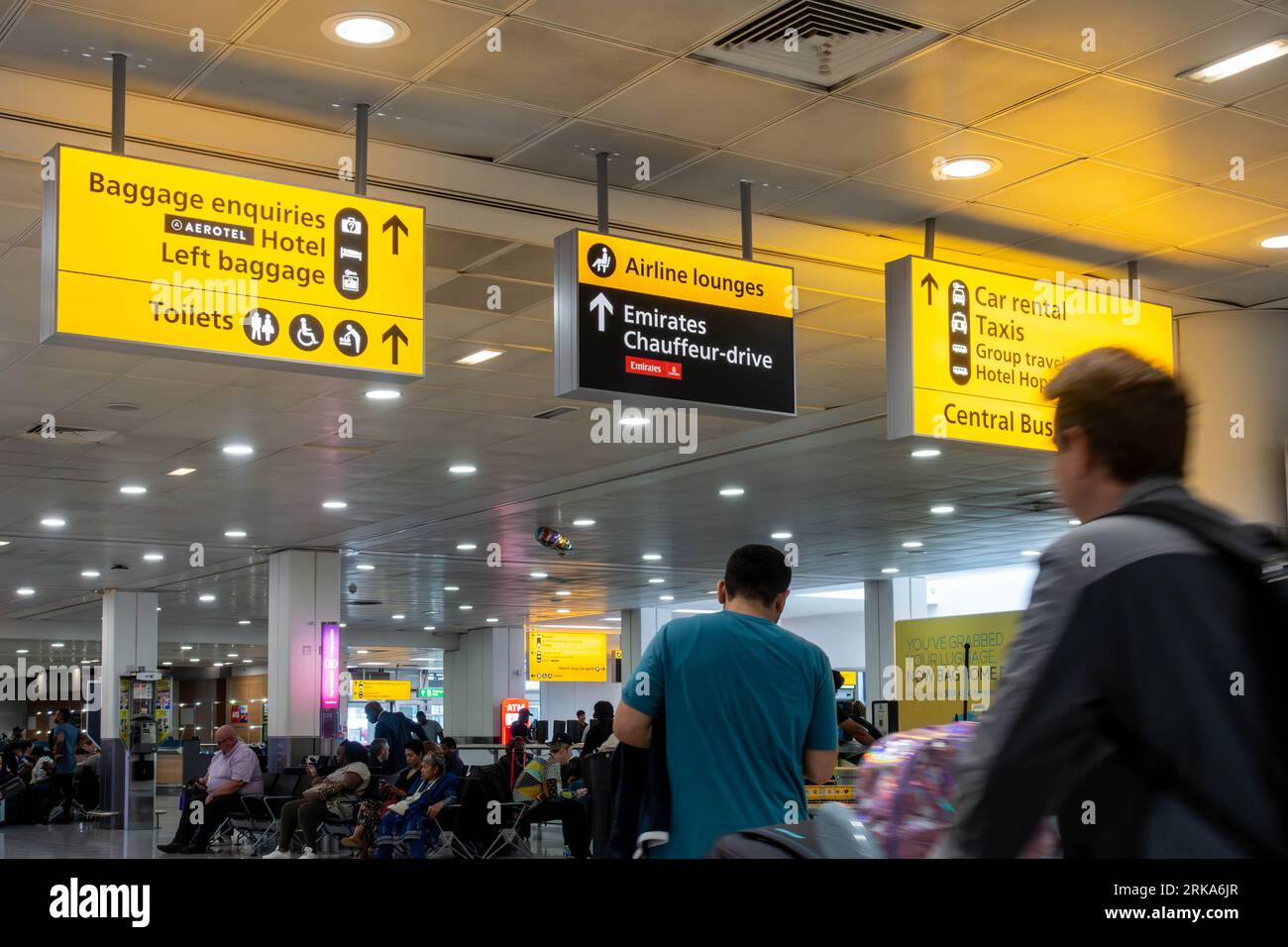 Yellow signs hanging from the ceiling give passengers directions at London Heathrow Airport ...