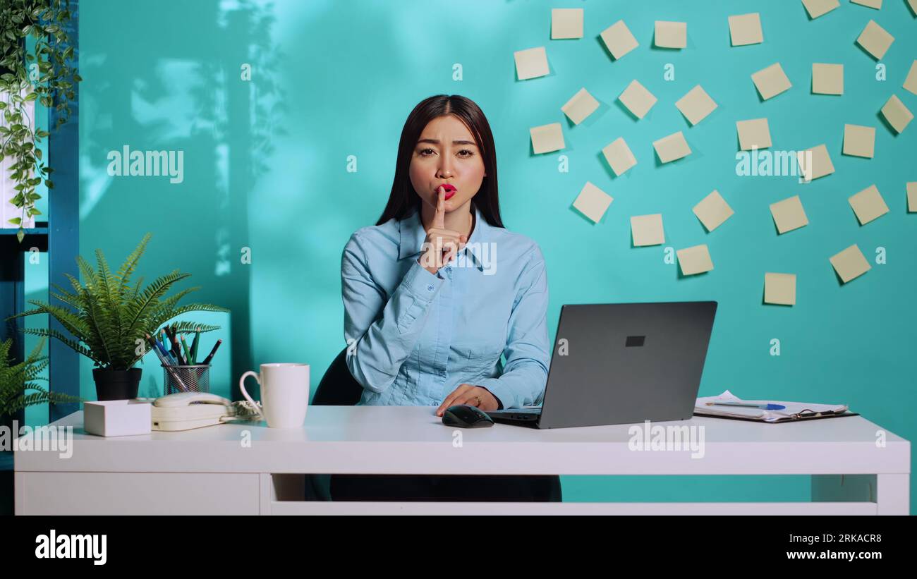 Stern serious businesswoman shushing at camera, holding quiet gesture ...