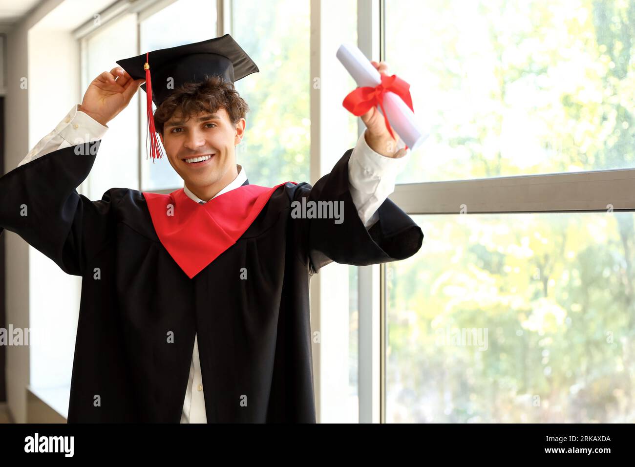 Male graduate student with diploma near window in room Stock Photo - Alamy