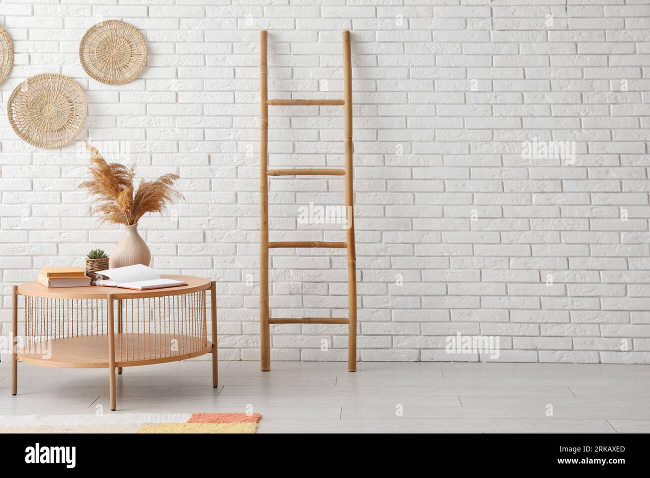 Light wooden coffee table with vase of dried pampas grass and ladder ...