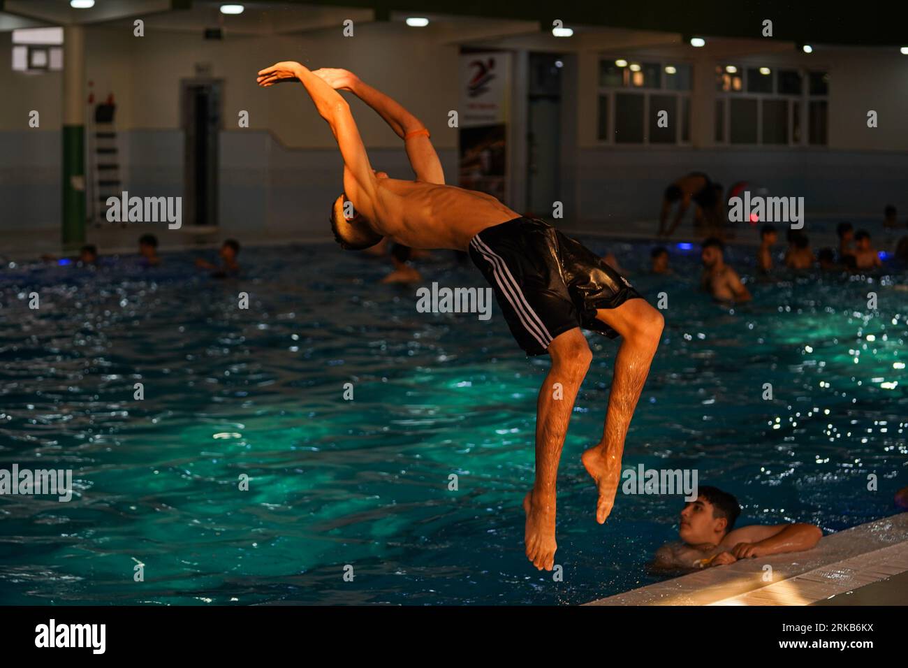 A young man jumps in a swimming pool to cool off on a hot summer day ...