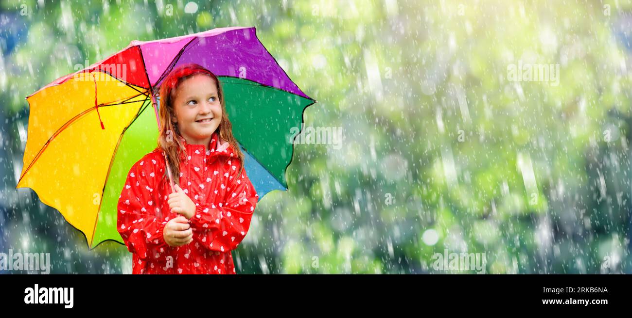 Kid playing in the rain in autumn park. Child with umbrella and rain ...