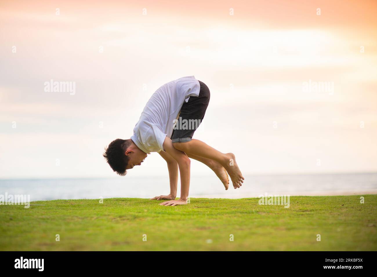 Teenager doing calisthenics exercise. Beach yoga at sunset. Teen boy ...