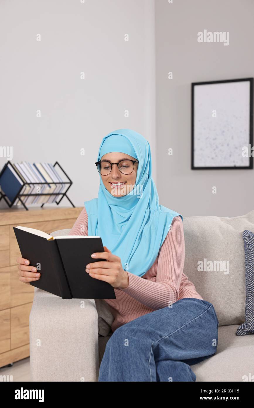 Muslim woman reading book on couch in room Stock Photo - Alamy