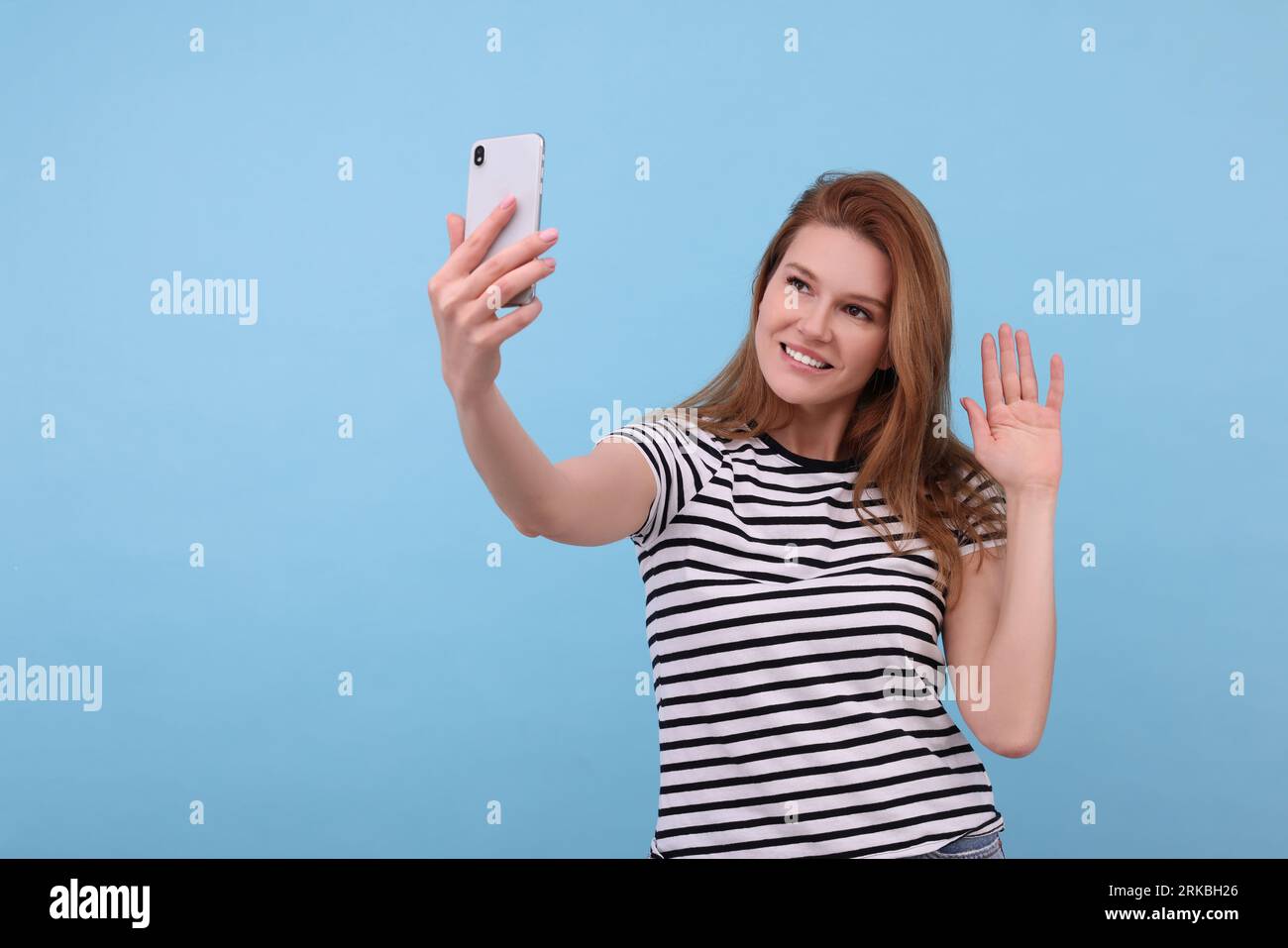 Beautiful woman taking selfie on light blue background Stock Photo - Alamy