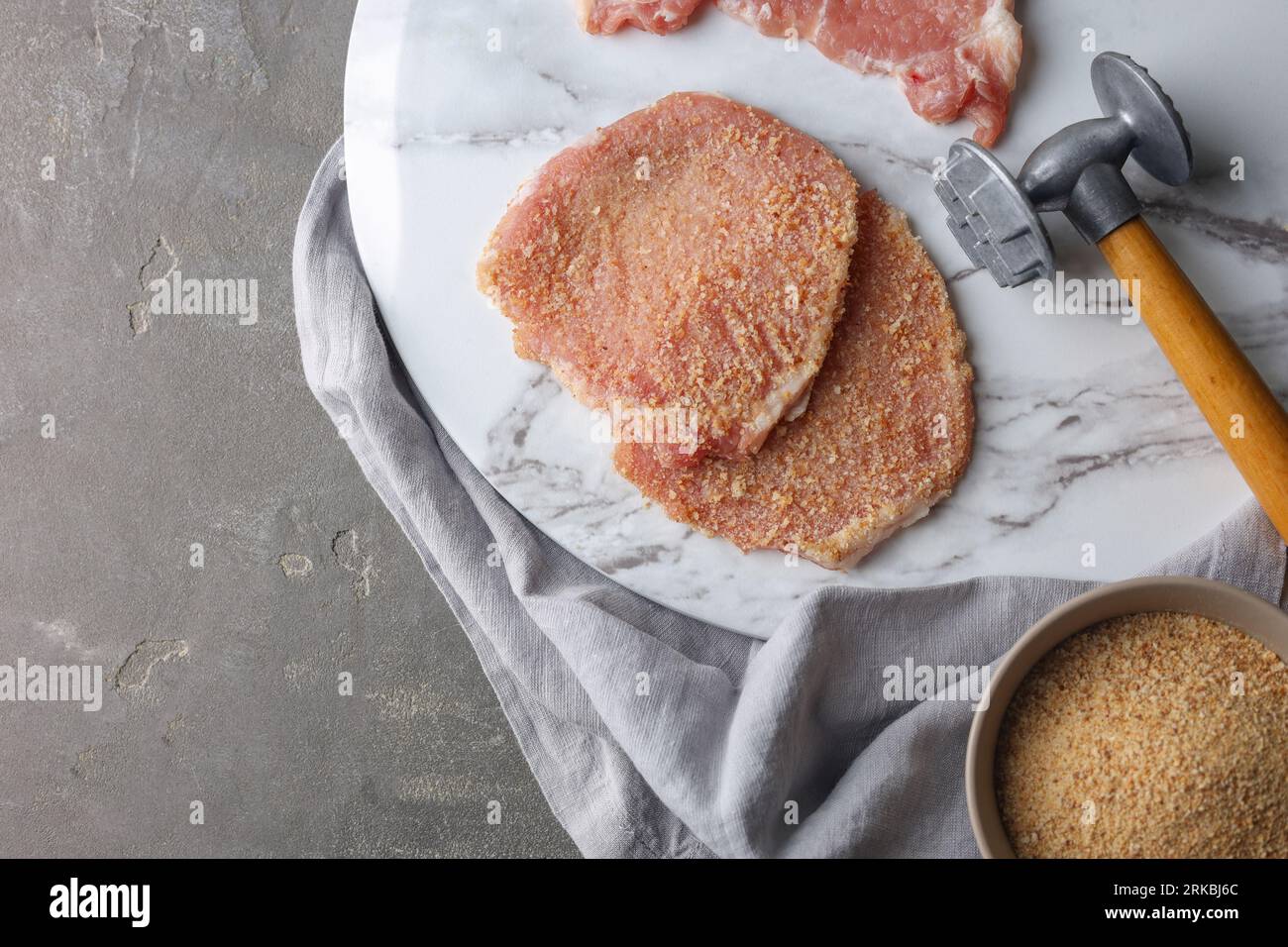 Cooking schnitzel. Raw pork chops in bread crumbs and meat mallet on ...