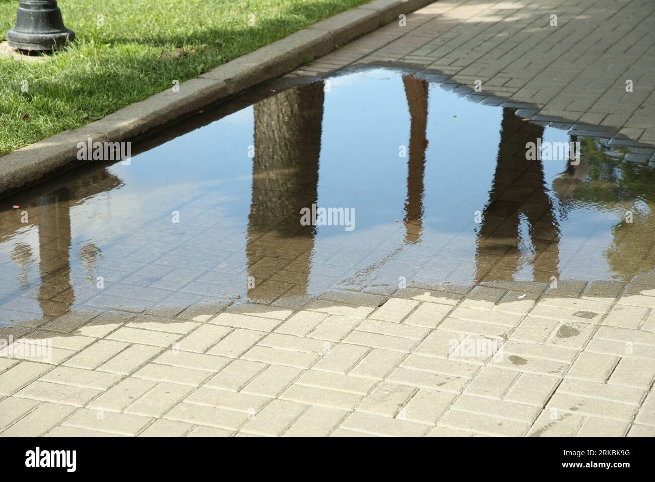 Puddle of rain water on paved pathway outdoors Stock Photo - Alamy