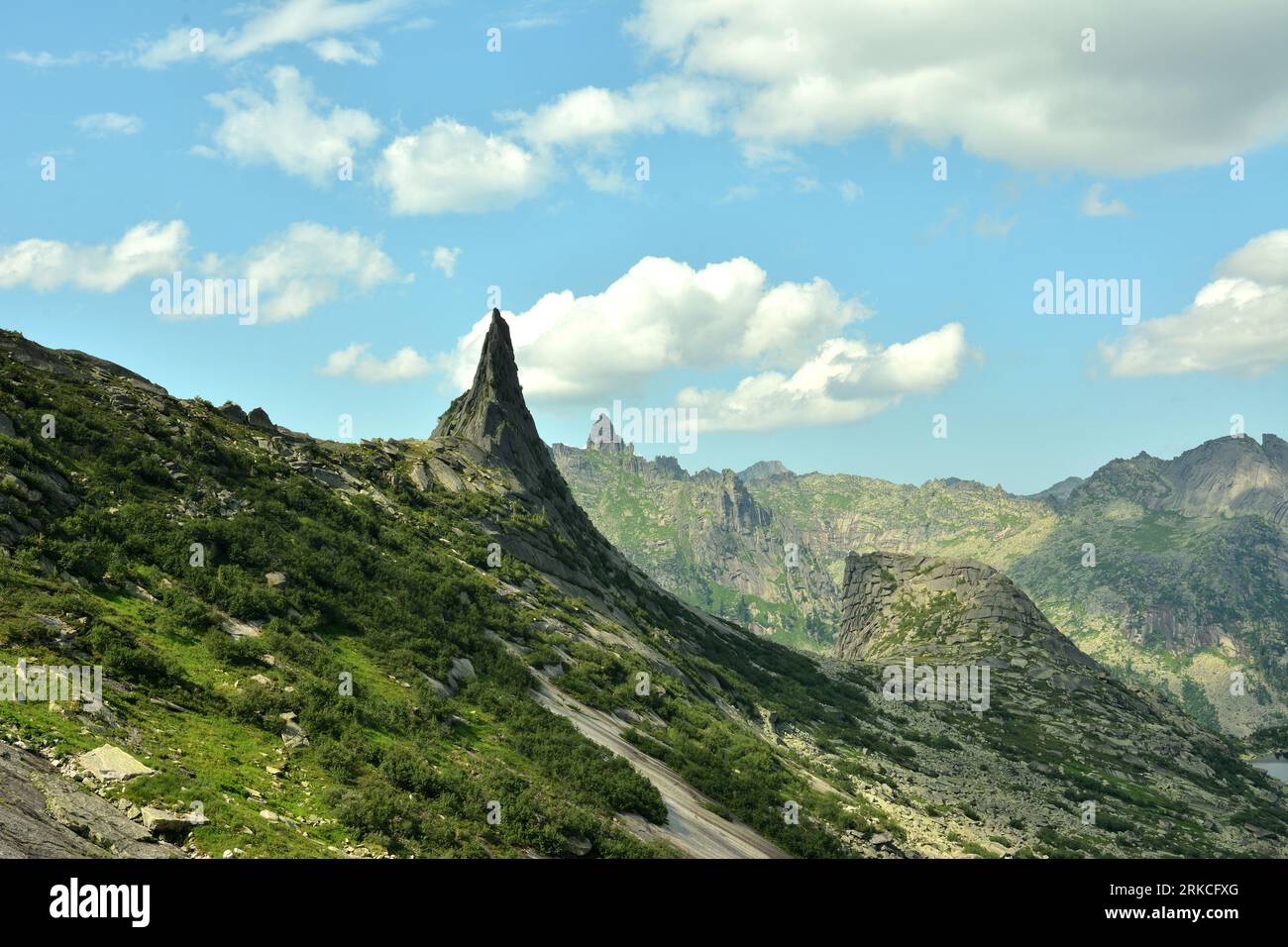 A gentle slope covered with moss and grass and two pointed peaks of a ...