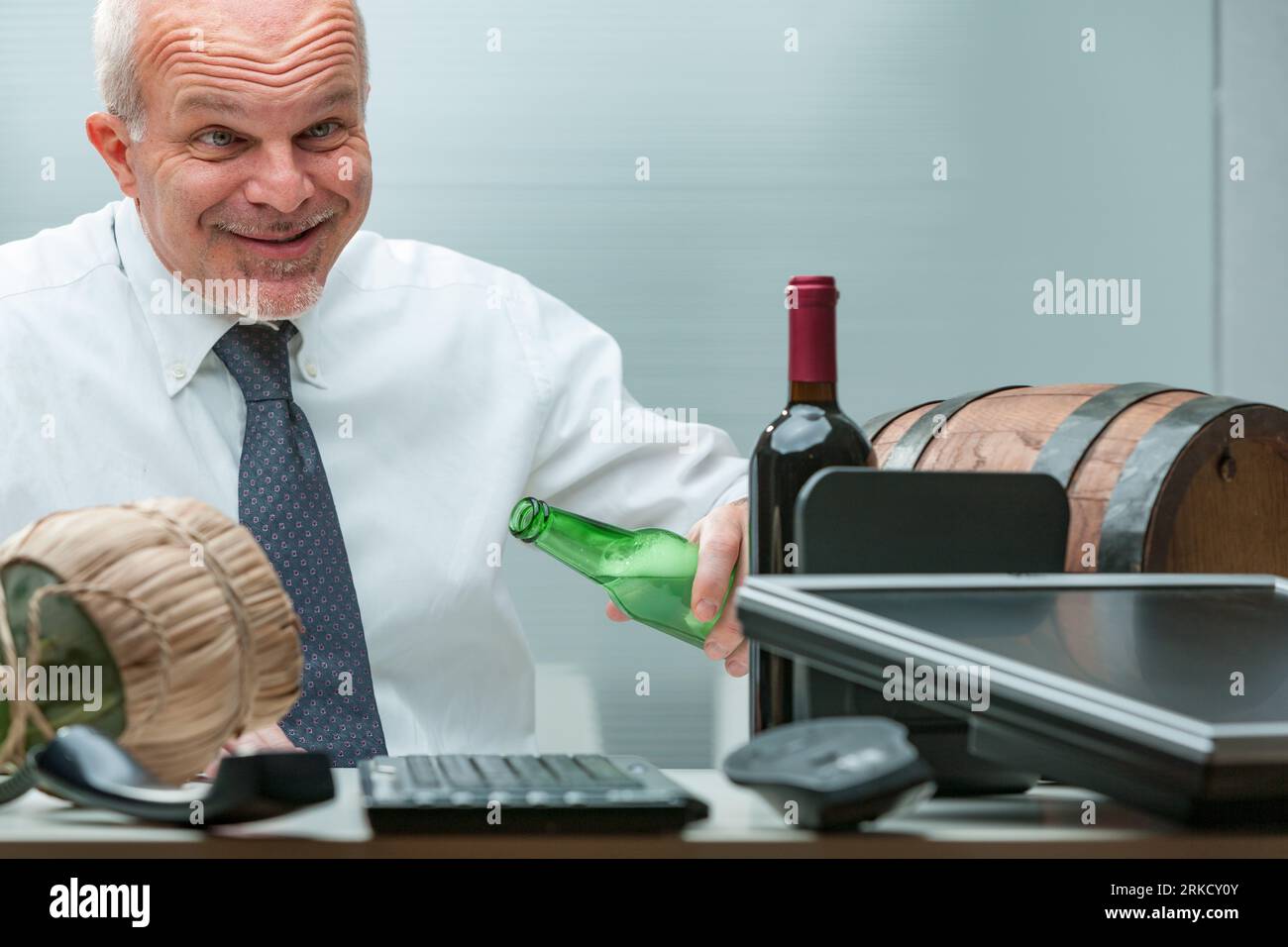 Man, looking foolish, overindulges in alcohol at the office ...