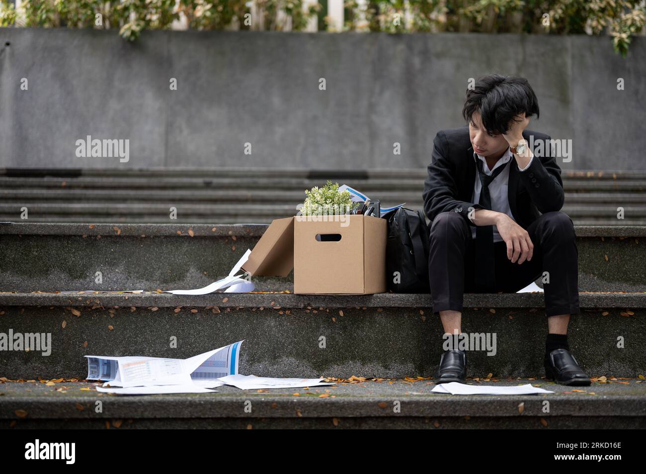 A depressed, upset, and sad young Asian unemployed businessman is ...