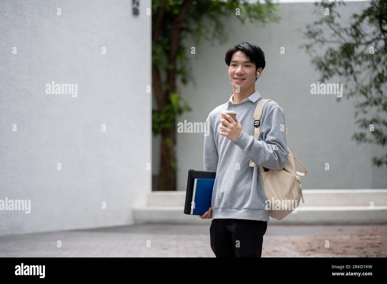 A handsome young Asian male student in casual clothes and his backpack ...