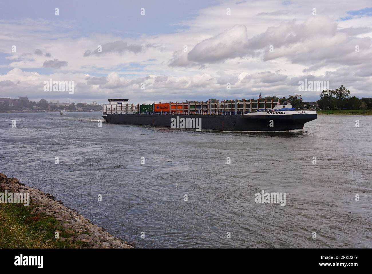 A large cargo ship sailing across the tranquil waters of Bonn, Germany ...