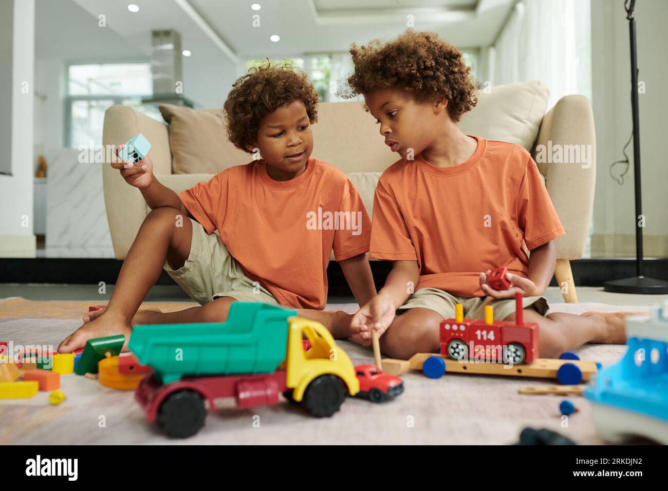 Cheerful children playing with toys on the floor in living room Stock ...