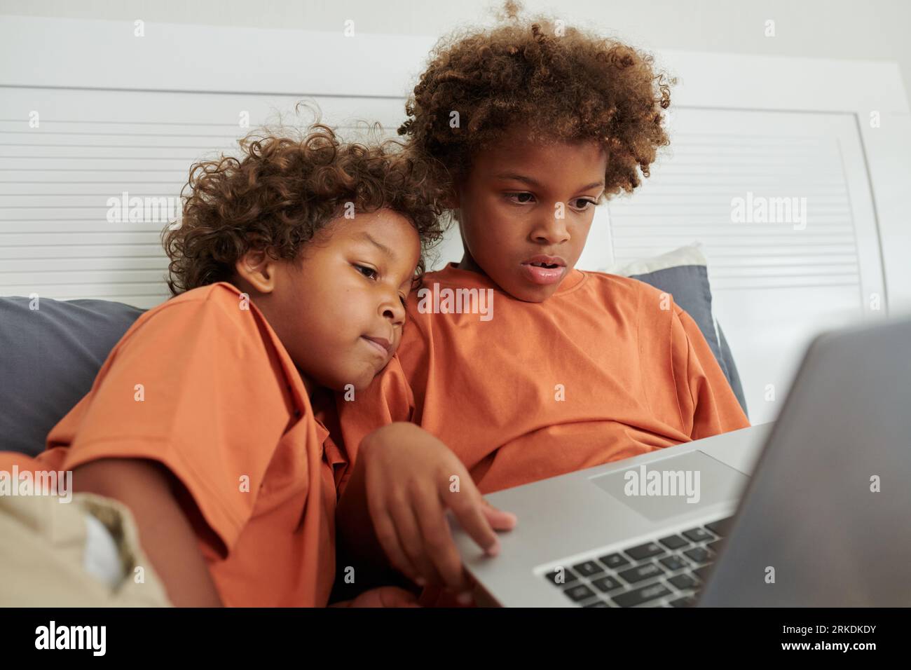 Little boy looking how his brother playing game on laptop when they are ...