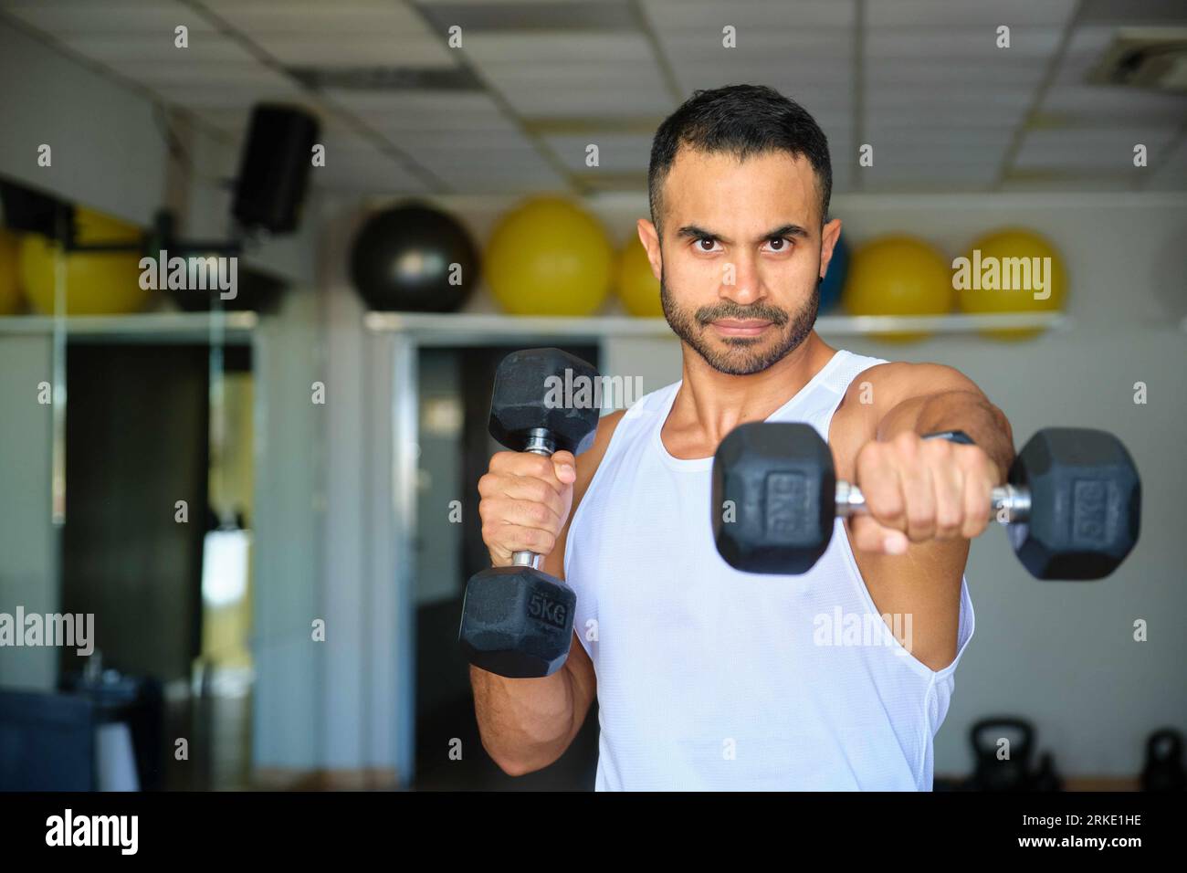 Strong Hispanic man doing dumbbell punches at a gym Stock Photo - Alamy