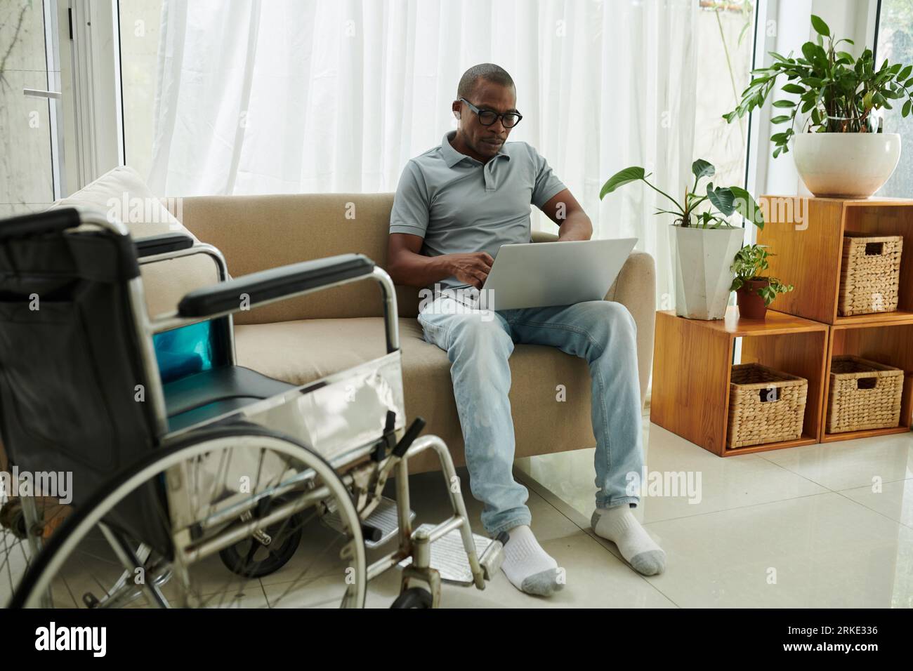 Man recovering from severe injury sitting on couch next to wheelchair ...