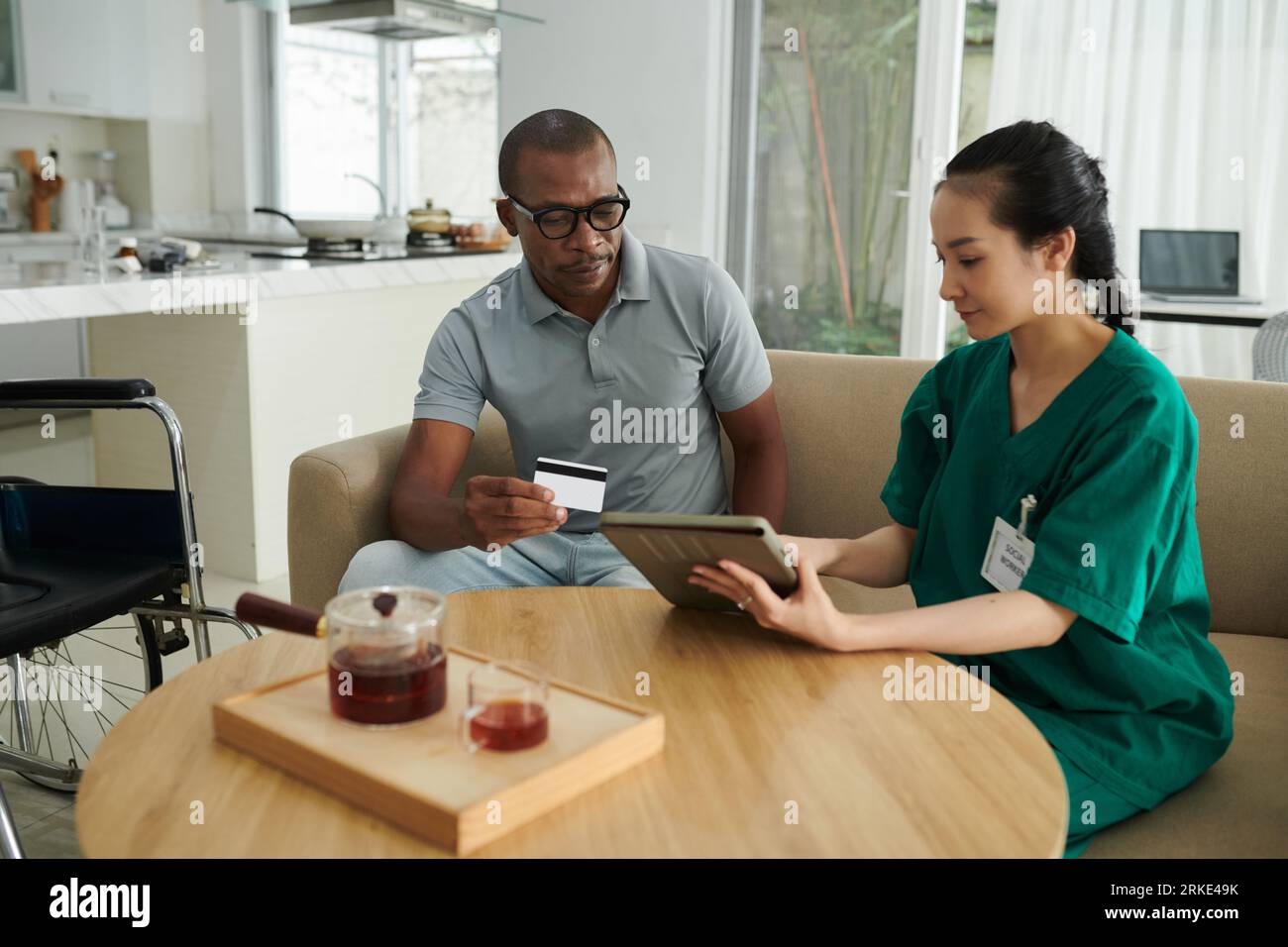 Social worker helping sick man to order medicine delivery online via ...